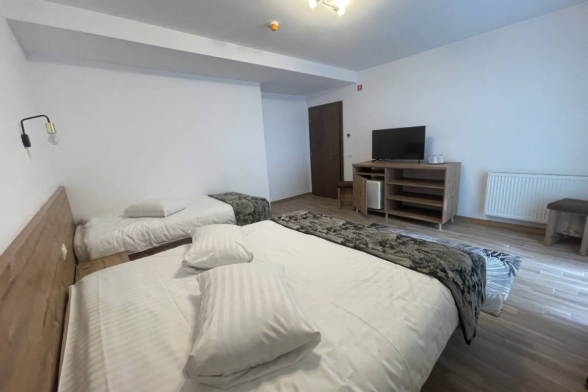 Quarto de hotel com duas camas, televisão, um pequeno armário e radiador.