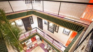Um átrio com vários níveis, espaço aberto central, grades decorativas e piso estampado.