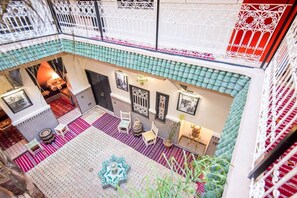 Um átrio amplo com vários níveis, piso de azulejos, guarda-corpos decorativos e diversas opções de assento.
