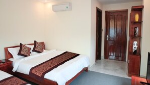 Quarto de hotel com duas camas, um guarda-roupa de madeira, uma televisão e um aparelho de ar condicionado.