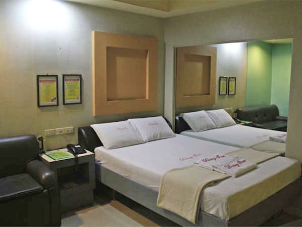 Quarto de hotel com duas camas, uma escrivaninha, uma cadeira e uma pequena mesa.