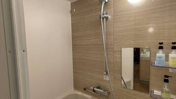 Uma casa de banho moderna com banheira, chuveiro e toucador com espelho e prateleiras.