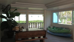 Quarto com um banco de madeira, um caiaque verde e um vaso de planta.