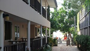 Uma área externa coberta com assentos, um caminho que leva a um edifício e vegetação.