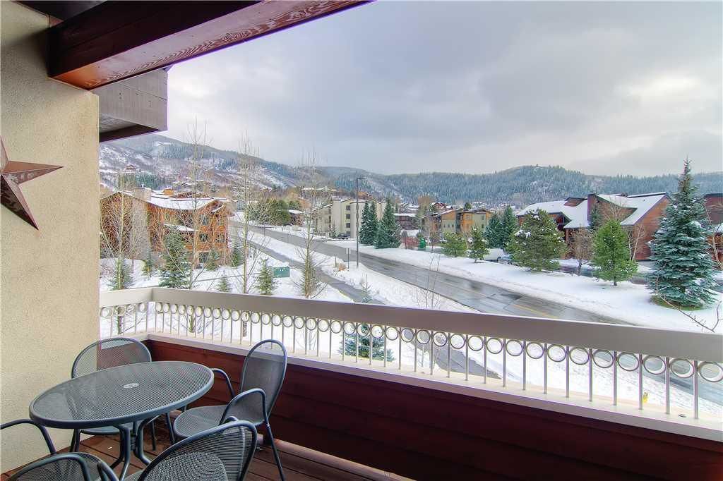 Varanda com vista para uma cidade coberta de neve, uma mesa e cadeiras.