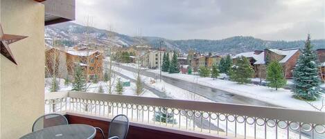 Varanda com vista para uma cidade coberta de neve, uma mesa e cadeiras.