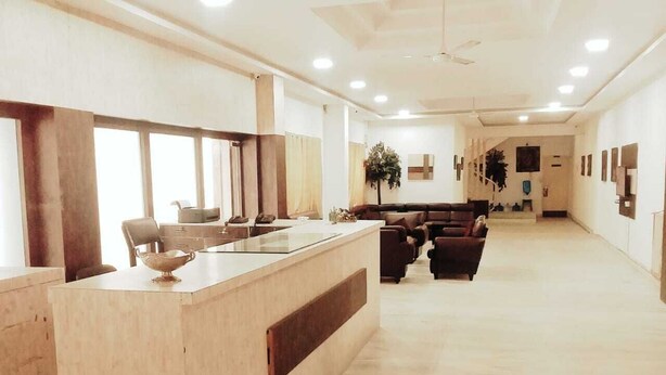 Um hall amplo com balcão de recepção, área de estar e escada para os andares superiores.
