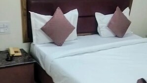 Cama com roupa de cama branca e duas almofadas castanhas grandes e quadradas.