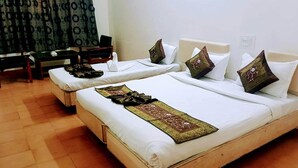 Quarto de hotel com duas camas de solteiro, uma mesinha e uma cadeira.