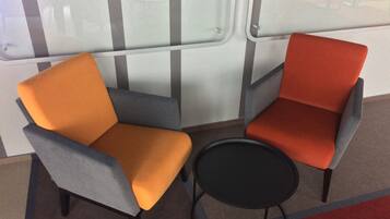Duas poltronas e uma mesinha num quarto com paredes listradas e um tapete estampado.