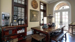 Quarto com mesa de madeira, máquina de café, relógio e um quadro pendurado na parede.