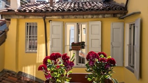 Um edifício amarelo com telhado telhado e venezianas brancas.