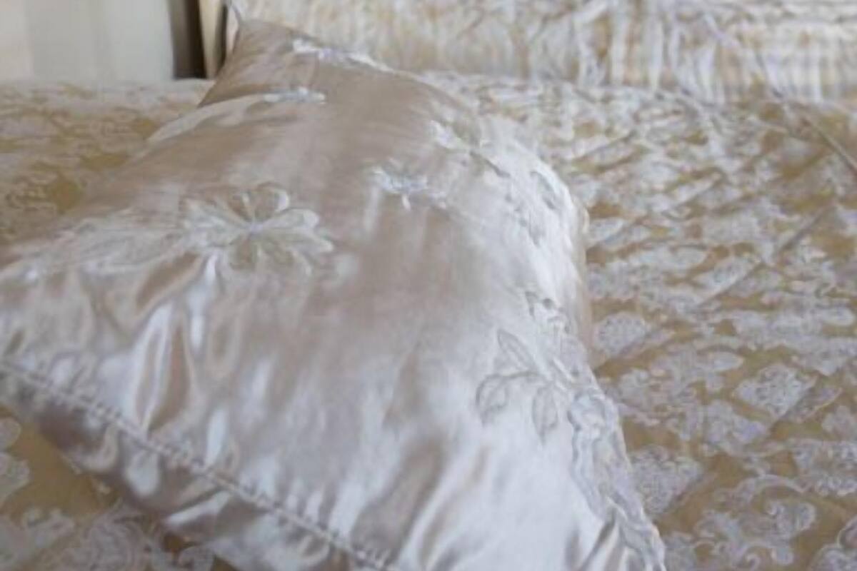 Quarto com duas camas, cada uma com cabeceira e travesseiros combinando.