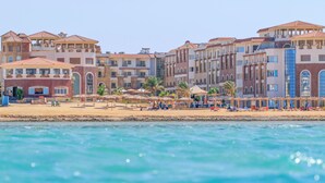 Um hotel na praia com vários edifícios, uma praia de areia e mar azul cristalino.