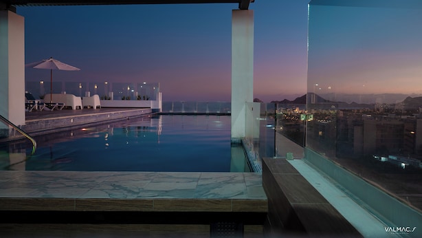 Uma piscina infinita com vista clara do horizonte da cidade ao entardecer.