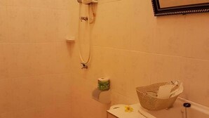 Casa de banho com sanita, chuveiro e lavatório.