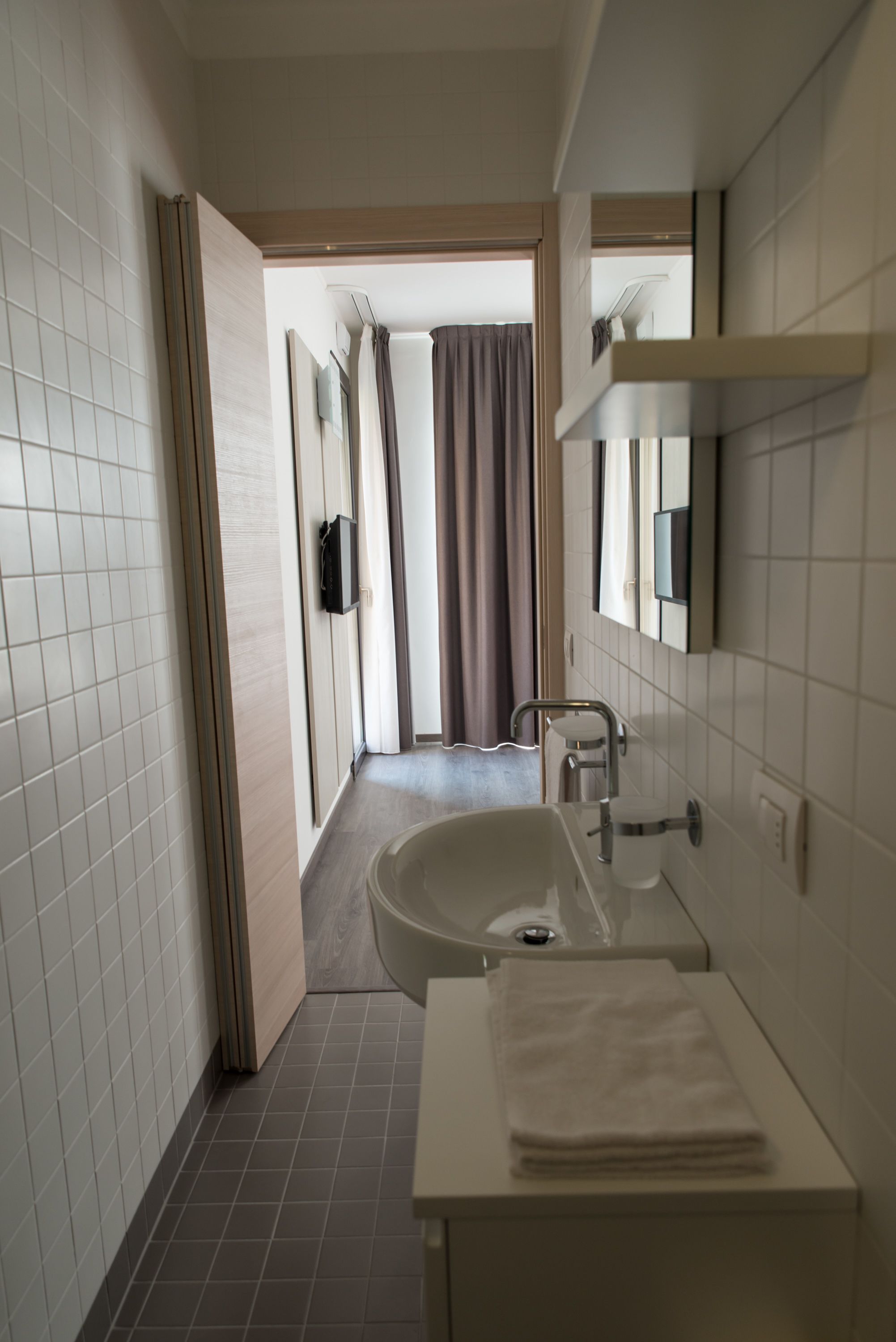 Casa de banho moderna com uma grande pia, espelho e porta-toalhas.