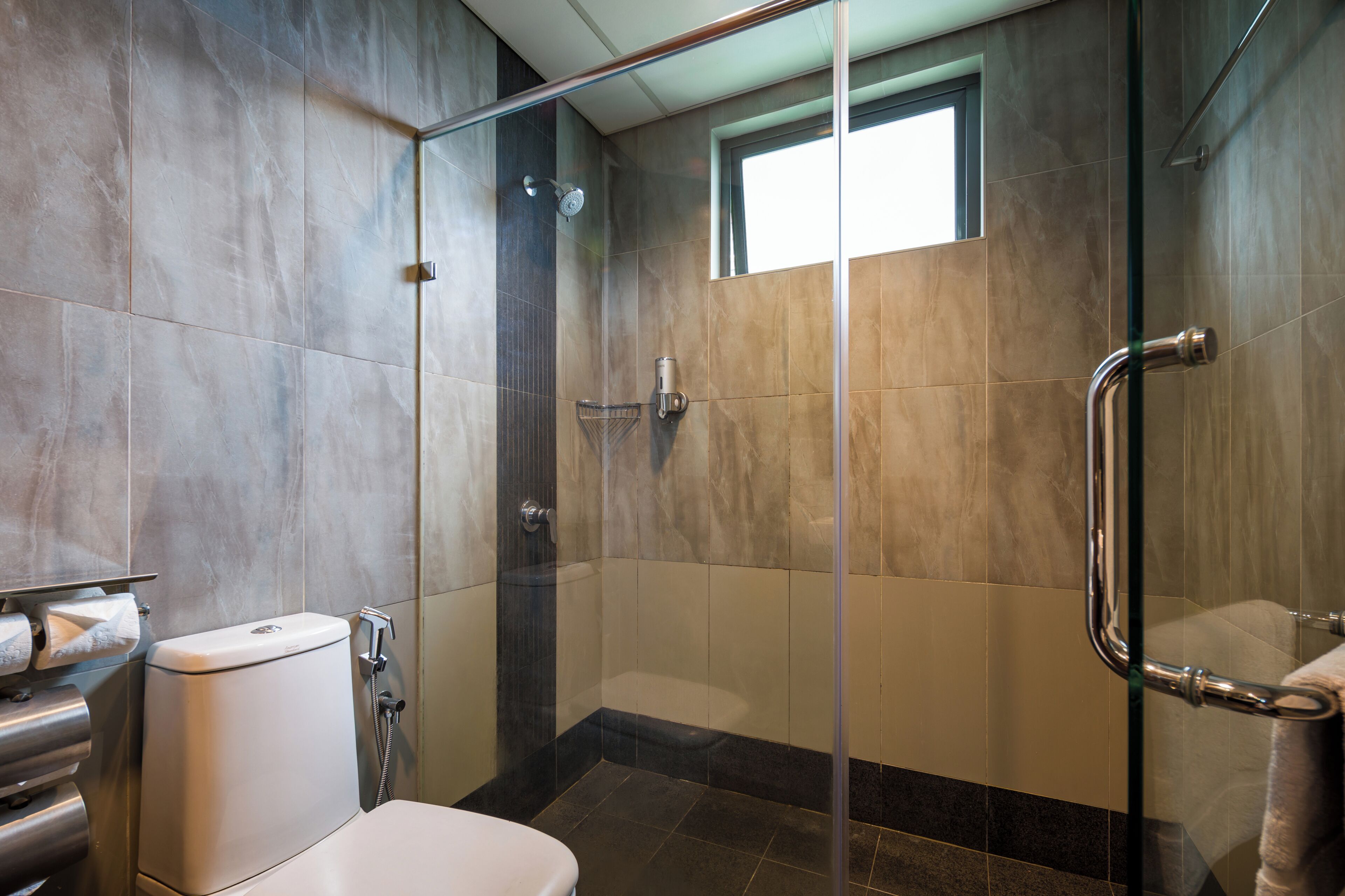 Uma casa de banho moderna com chuveiro separado por vidro, sanita e suporte para toalhas.