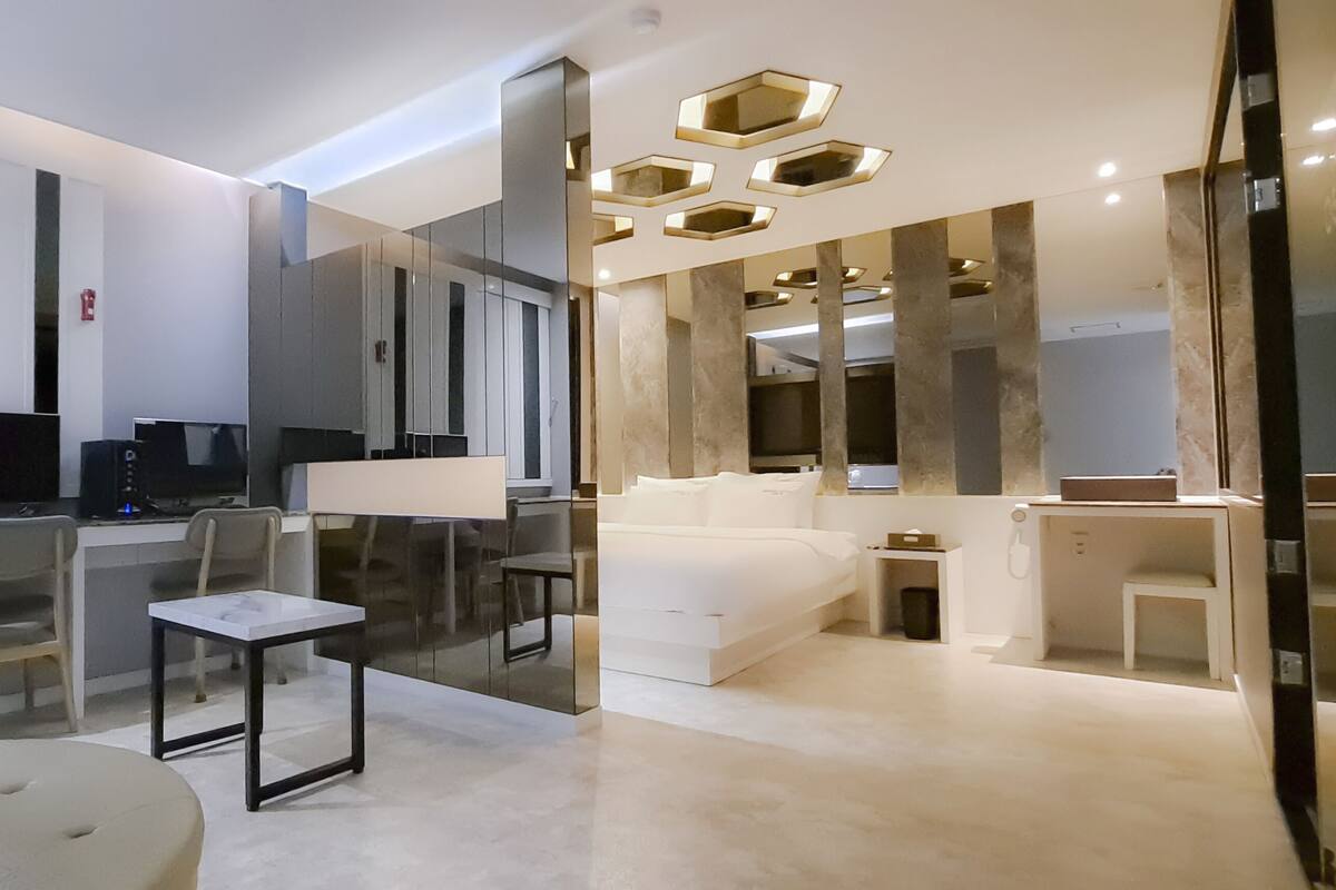 Quarto de hotel moderno com escrivaninha, computador, cadeira e cama.