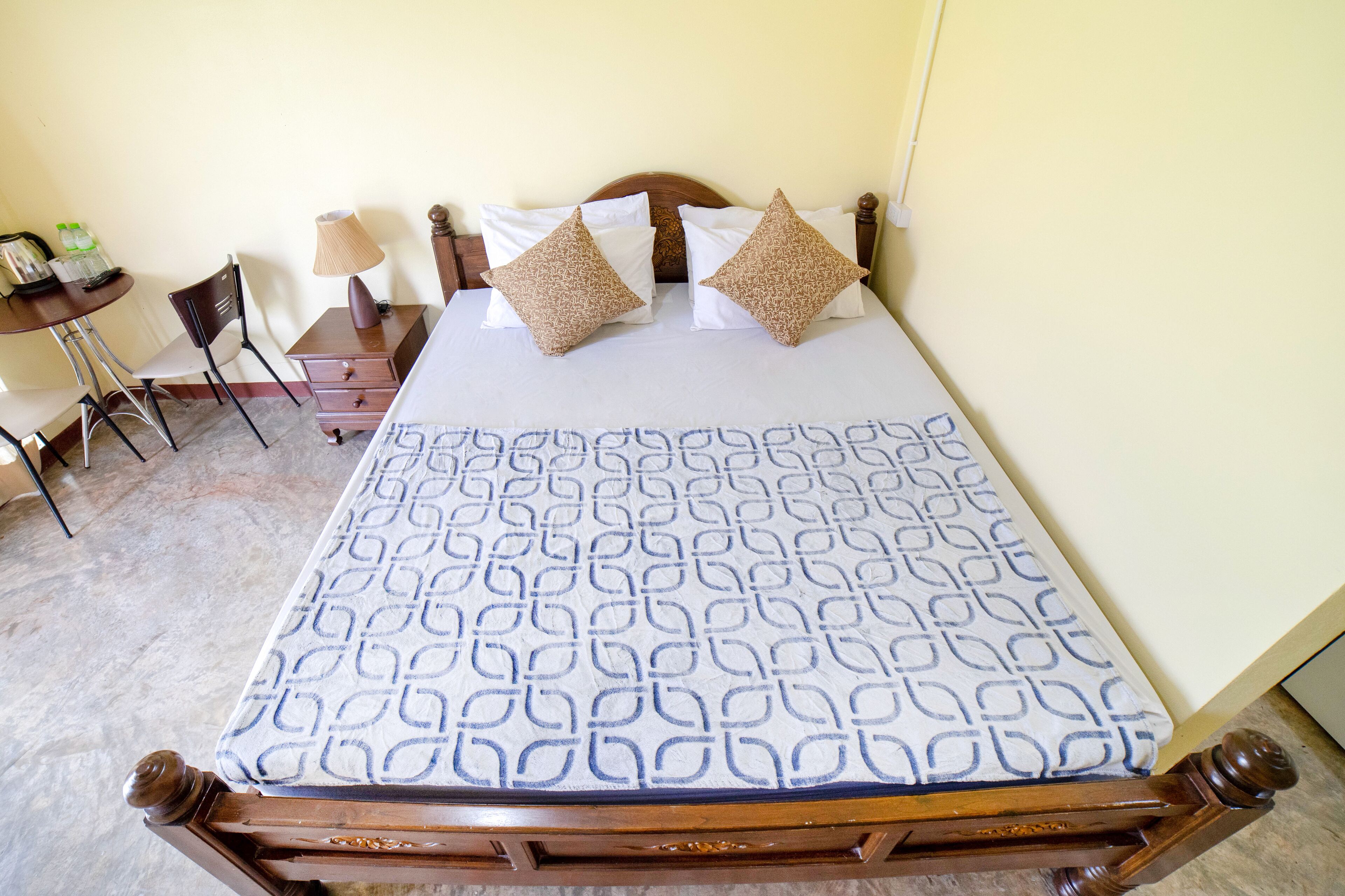 Uma cama bem arrumada com roupa de cama estampada, cabeceira de madeira e dois travesseiros.
