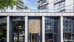 A entrada do edifício Mennica Residence com uma grande placa '4A' e portas de vidro.