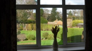 Uma janela com vista para um jardim e uma casa.