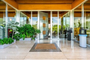 Uma entrada moderna com portas de vidro, plantas em vasos e piso de azulejos limpo.