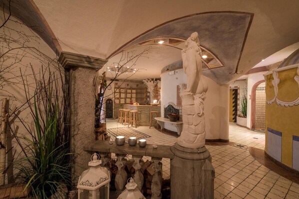 Amplo interior com teto alto, uma coluna central e vista para uma sala de jantar.