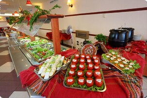 Disposição de buffet com diversos alimentos, incluindo saladas, sanduíches e tomates decorados.