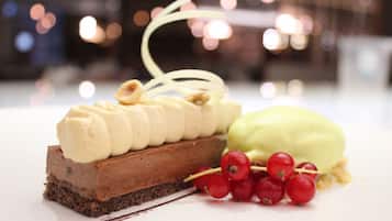 Sobremesa com base de chocolate e cobertura branca, acompanhada de frutas vermelhas e uma fruta amarela.