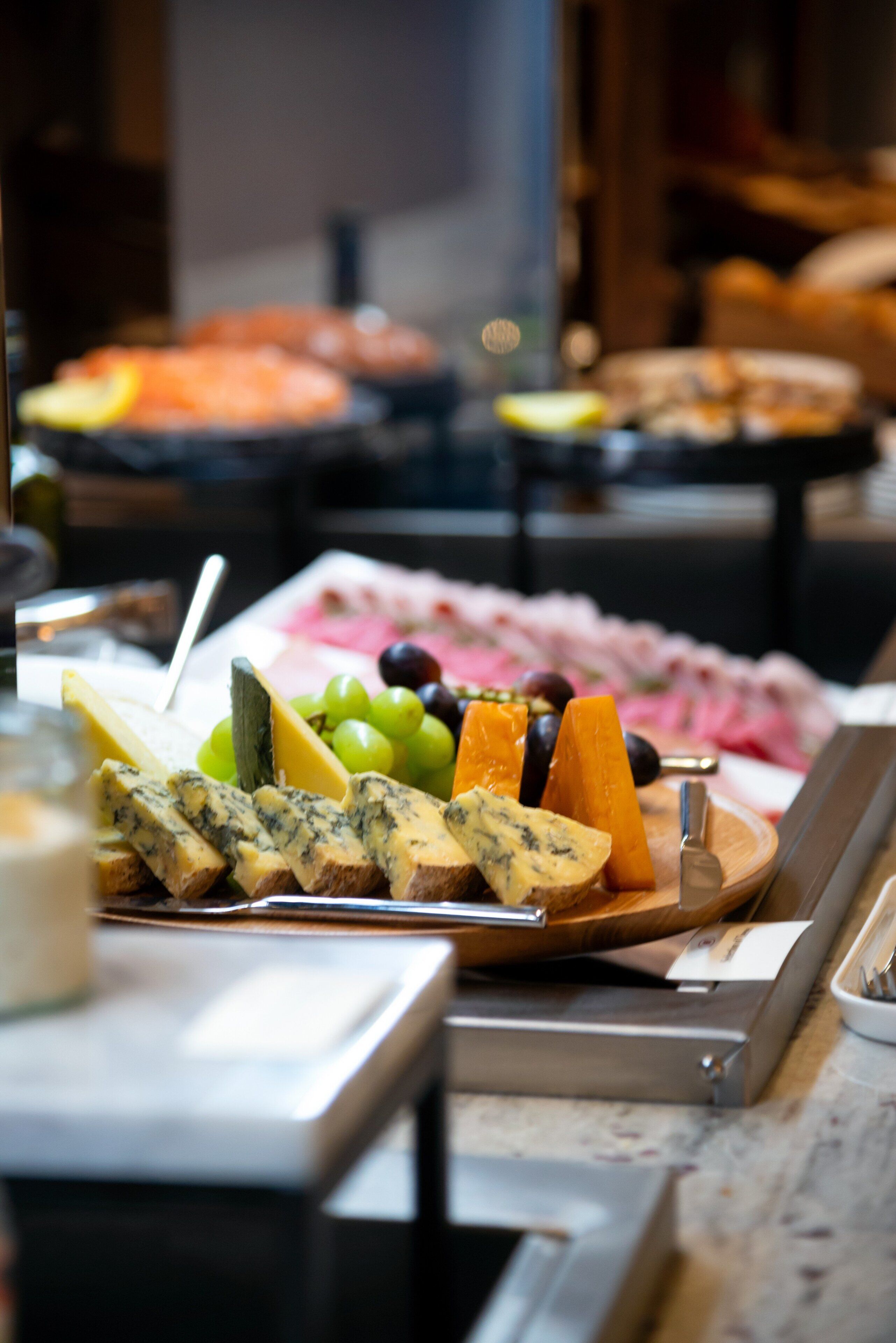 Buffet com diversos itens de comida, incluindo queijo, frutas e legumes.