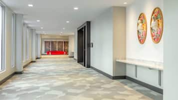 Um corredor com piso estampado, uma mesa de recepção e duas obras de arte fixadas na parede.