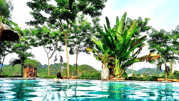 Piscina límpida rodeada por vegetação exuberante e um cenário montanhoso.