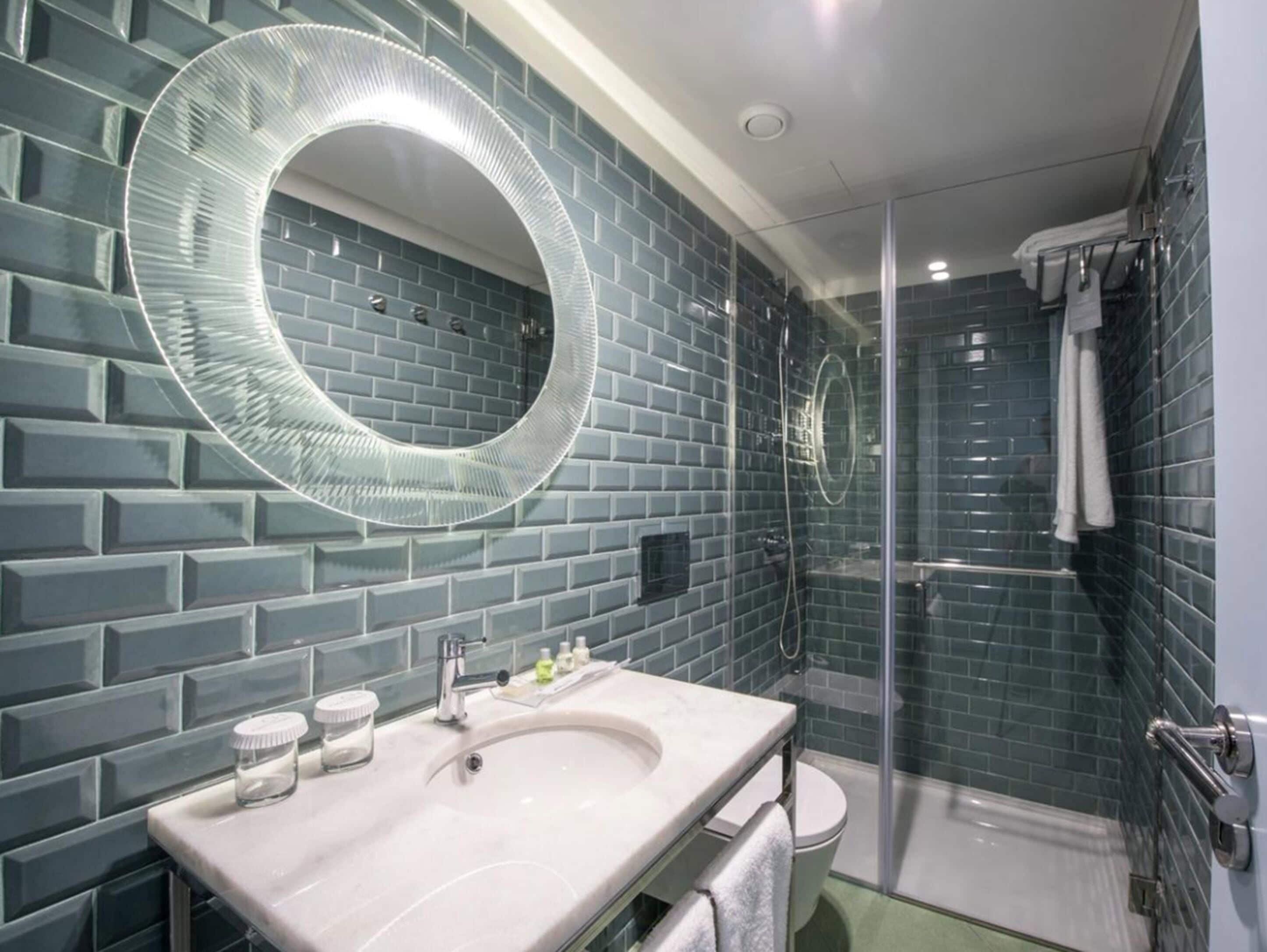 Uma casa de banho moderna com um espelho grande, uma pia e um chuveiro com parede de vidro.