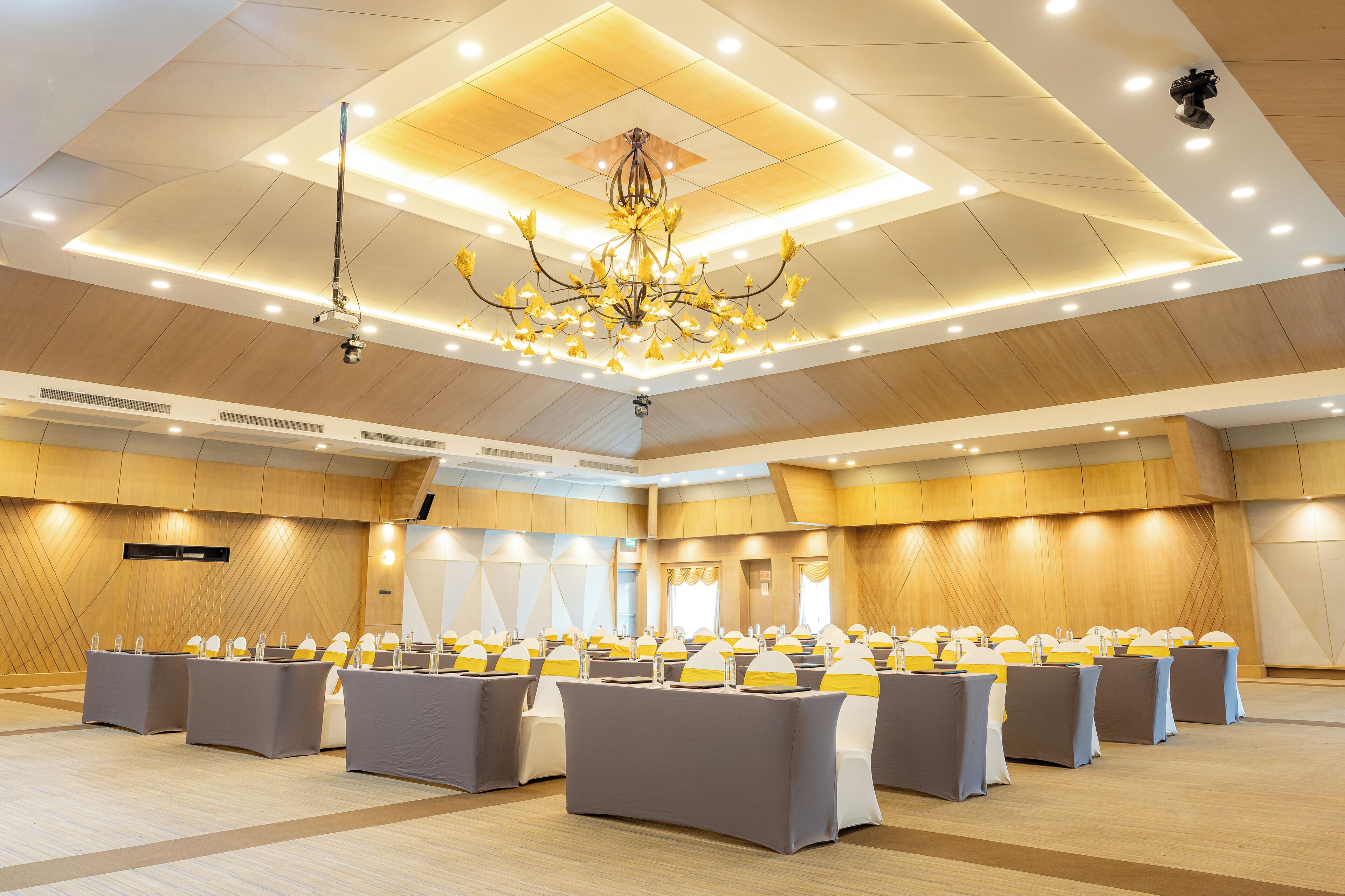 Uma sala de conferências com mesas dispostas em fileiras, um candelabro e iluminação embutida.