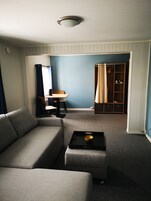 Uma sala de estar com sofá, mesa de centro, mesa de jantar com cadeiras e um guarda-roupa.