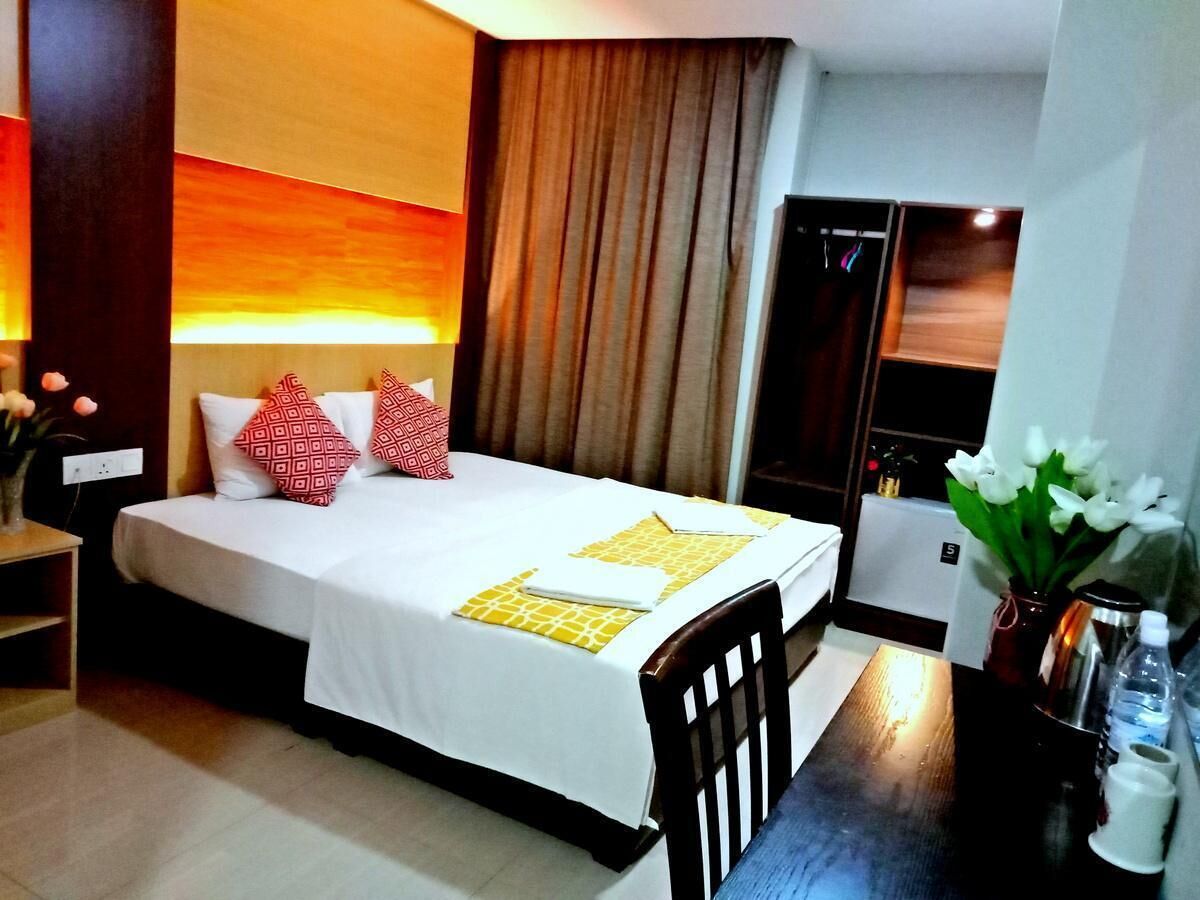 Quarto de hotel com cama, mesa de cabeceira e criado-mudo.