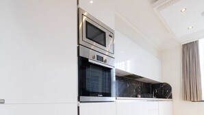Uma cafeteira/bule, um frigorífico, um micro-ondas, um forno 