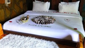 Uma cama com um letreiro 'WELCOME', um leque decorativo e uma garrafa sobre a cama.