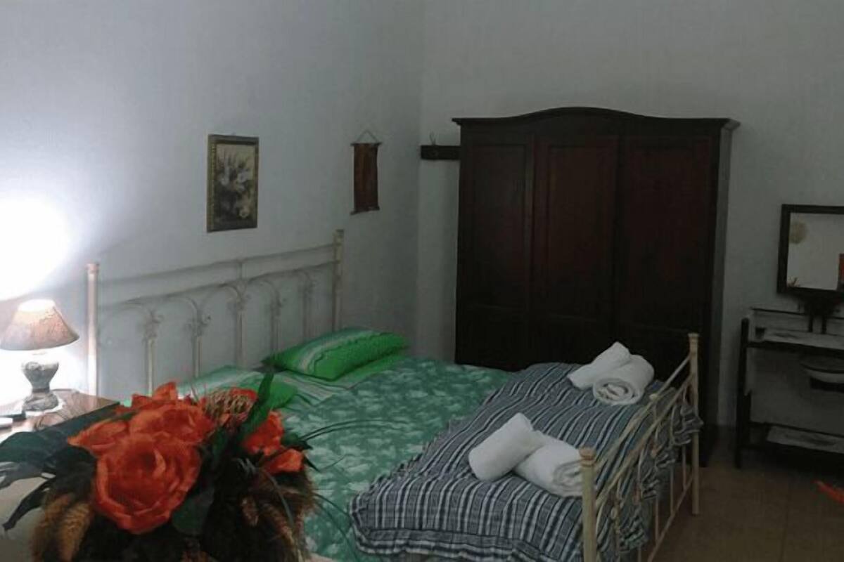Quarto com cama, mesa de cabeceira, abajur, espelho e guarda-roupa.