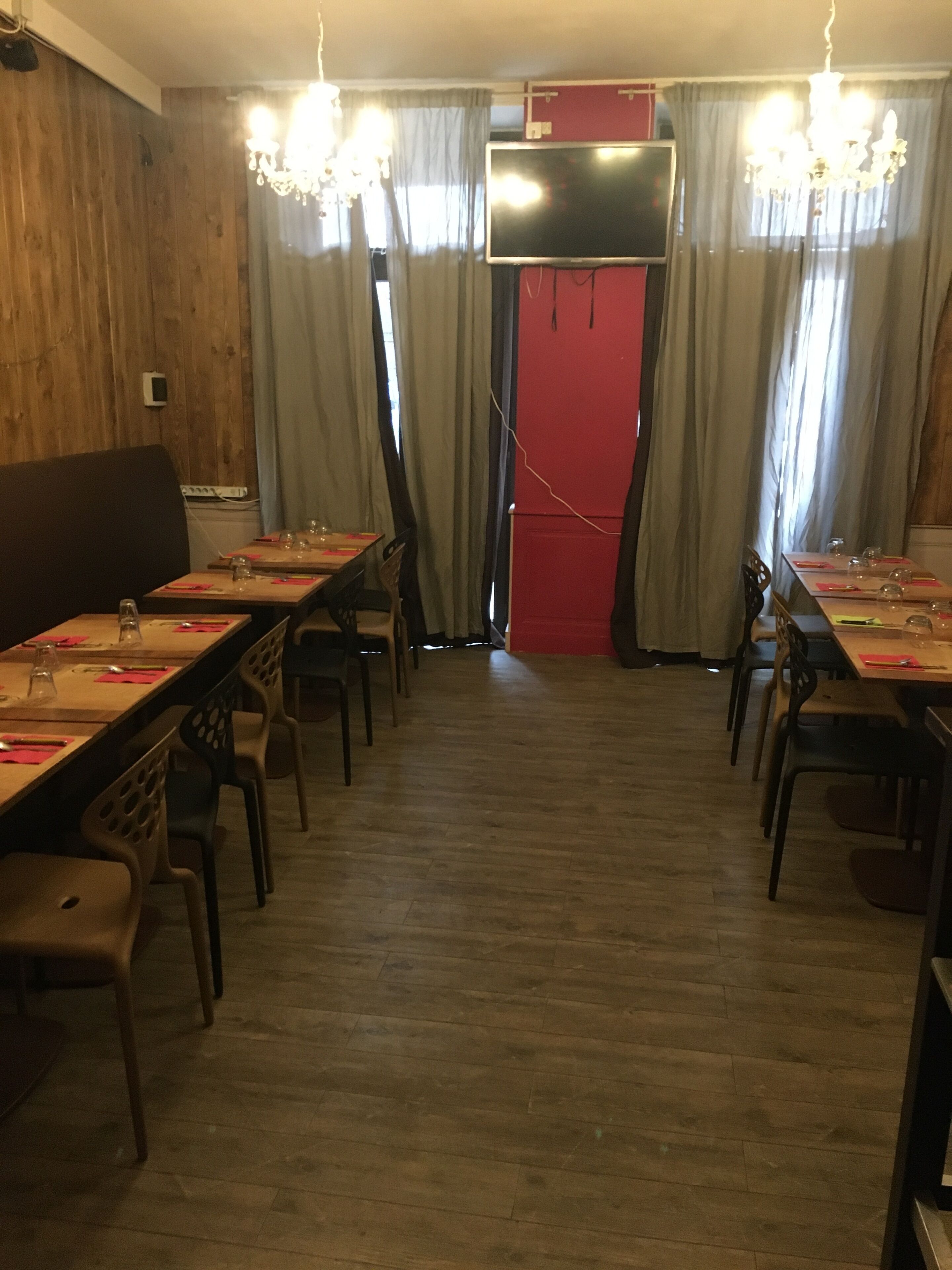 Uma sala de conferências com mesas compridas, cadeiras, uma TV de tela plana e lustres.
