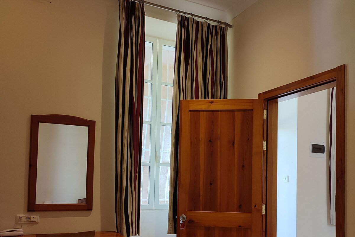 Quarto de hotel com escrivaninha de madeira, cadeira e cama.