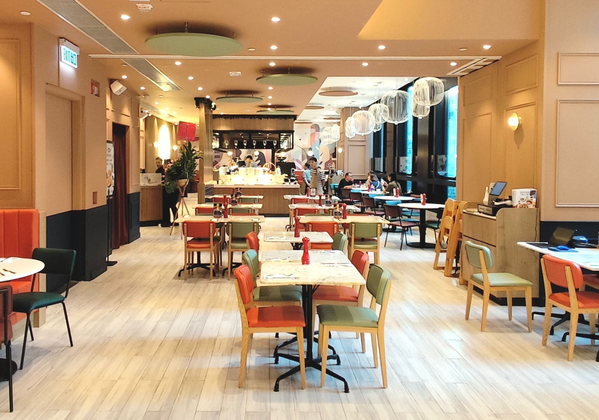 Um restaurante espaçoso com várias mesas e cadeiras, um bar e uma saída visível.