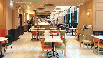 Um restaurante espaçoso com várias mesas e cadeiras, um bar e uma saída visível.