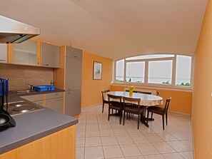 Cozinha com área de jantar, vista para o mar através de uma grande janela e piso de azulejos.