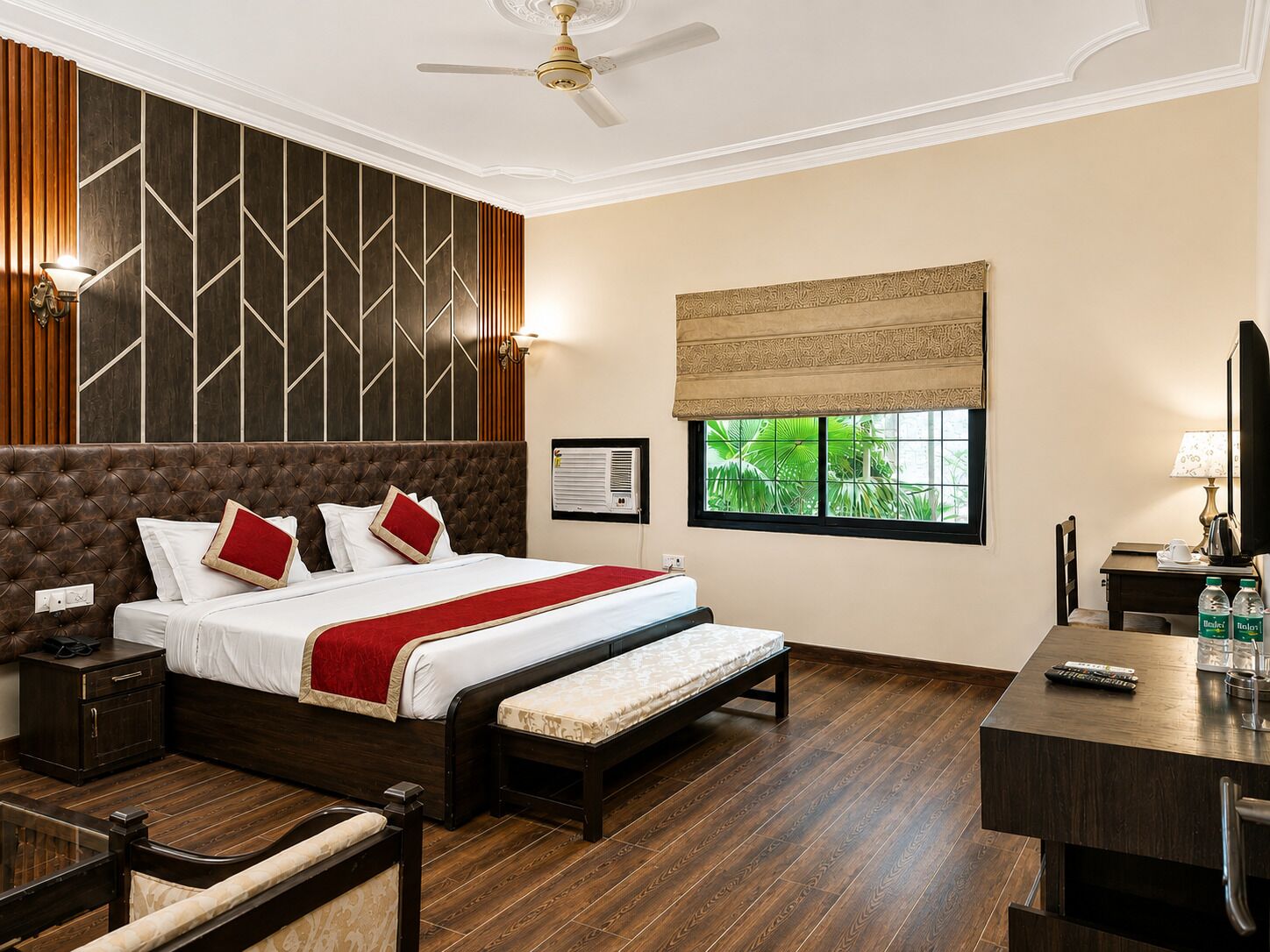Quarto de hotel com cama, mesa de cabeceira, escrivaninha e secretária com cadeira.