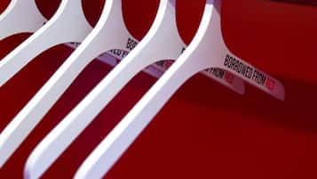 Um cabideiro com ganchos brancos e fundo vermelho.