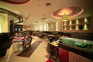 Um restaurante moderno com uma mesa comunitária grande, mesas individuais e um balcão com uma escultura decorativa de peixe.