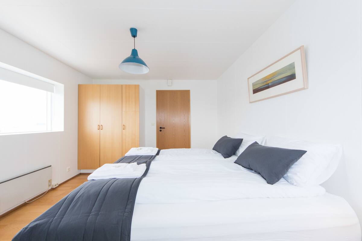 Quarto com cama, guarda-roupa, porta e luz no teto.
