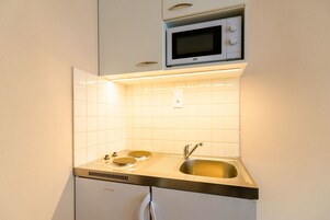 Uma cozinha compacta com micro-ondas, duas bocas e uma pia.